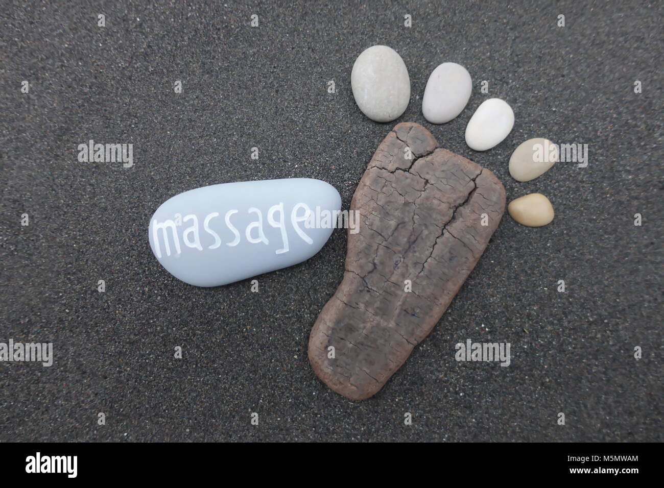 Massage text on a stone with pebbles foot over black volcanic sand ...