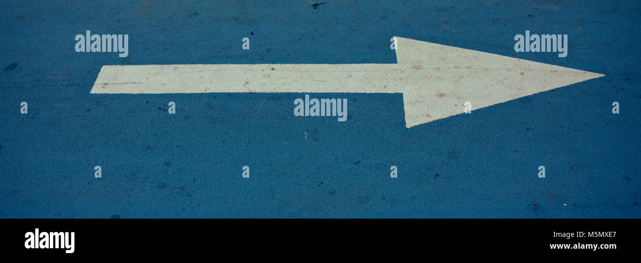 Arrow. White arrow on the blue floor. Road sign Stock Photo - Alamy