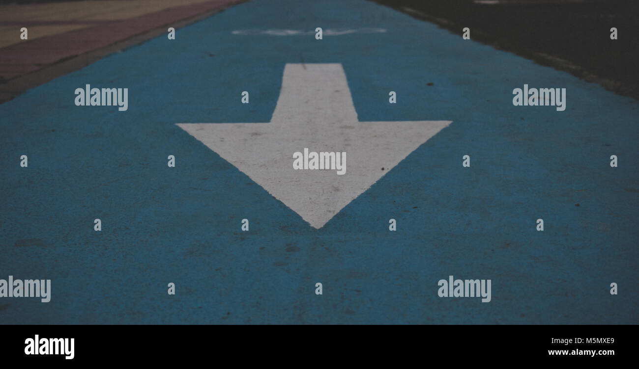 Arrow. White arrow on the blue floor. Road sign Stock Photo - Alamy