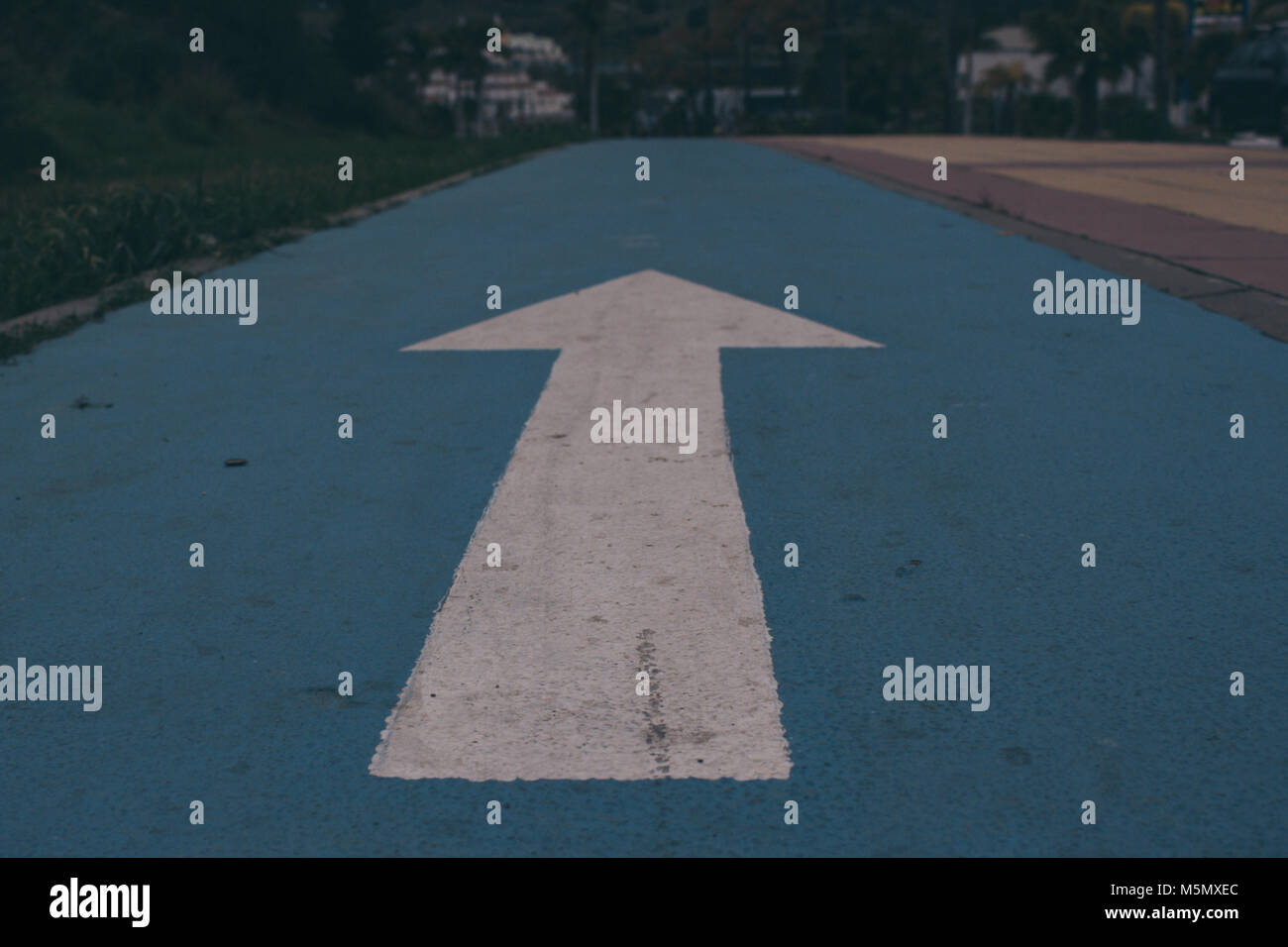 Arrow. White arrow on the blue floor. Road sign Stock Photo - Alamy