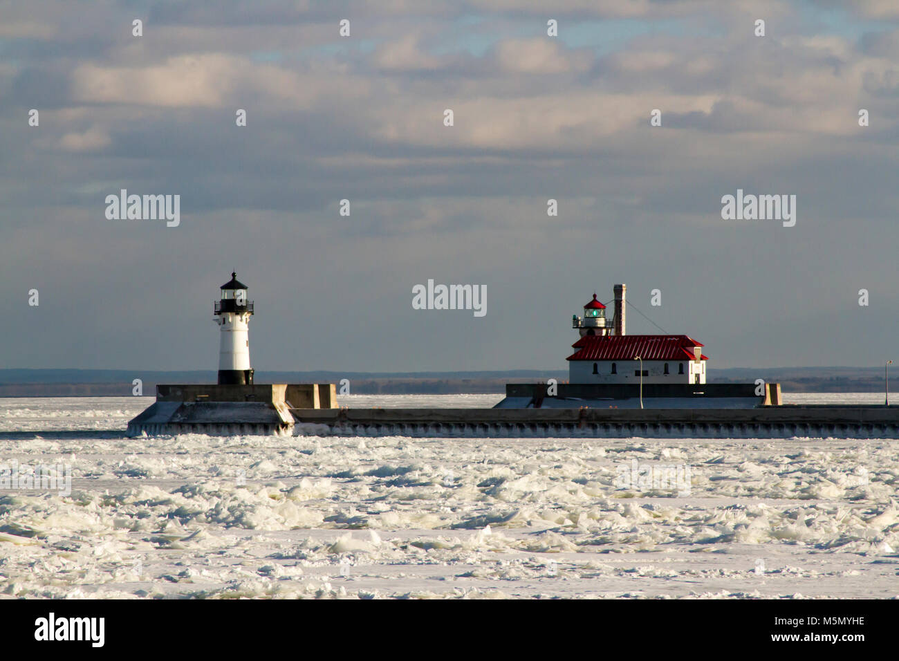Frozen Lake Superior shoreline with lighthouses and shipping pier in ...