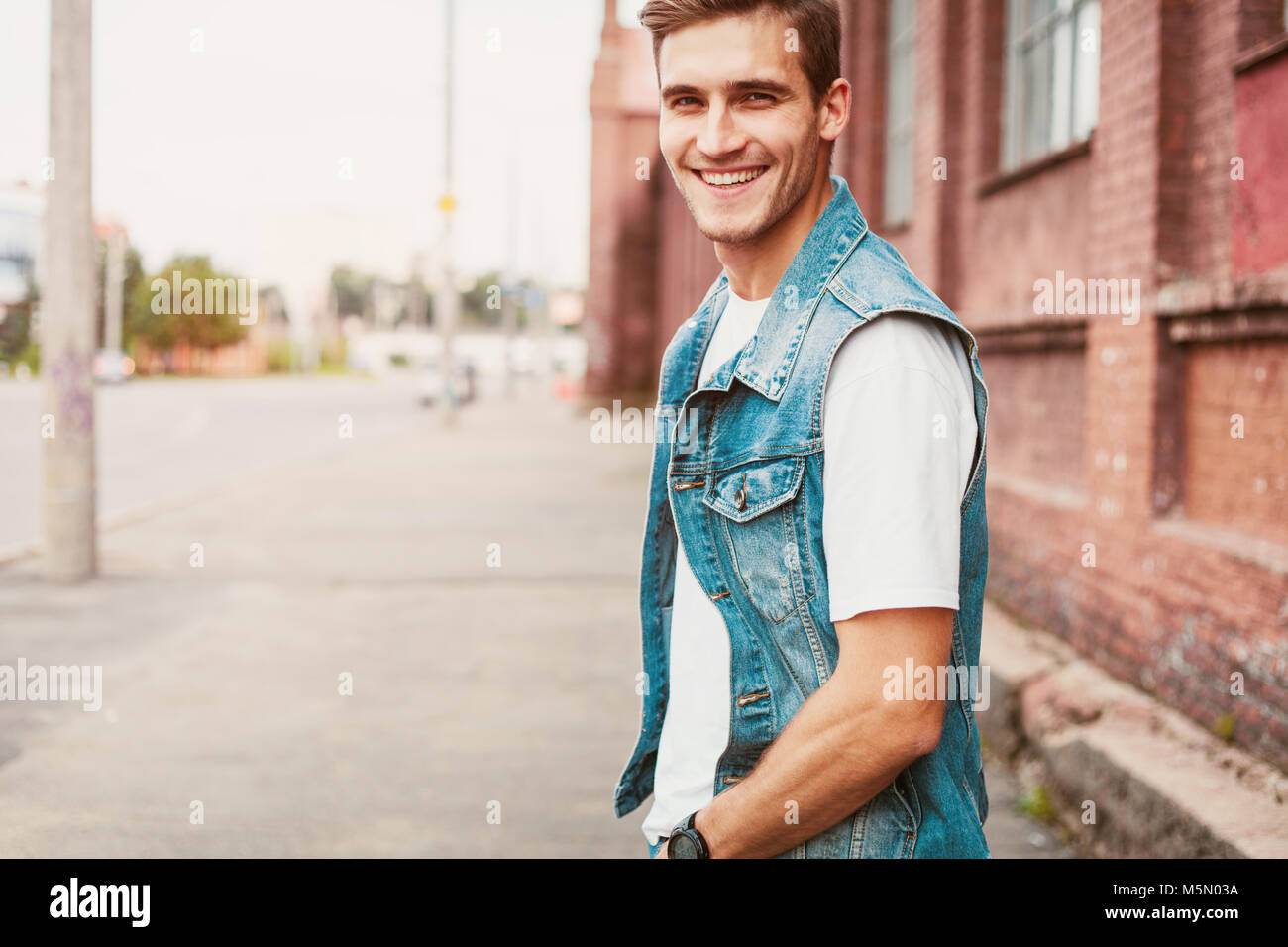 casual young man stands with his back against a brick wall Stock Photo ...