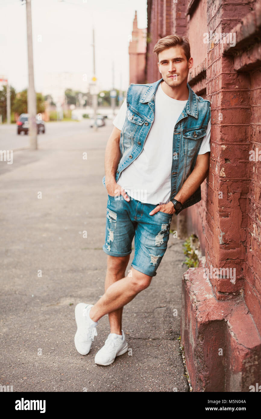 casual young man stands with his back against a brick wall Stock Photo ...