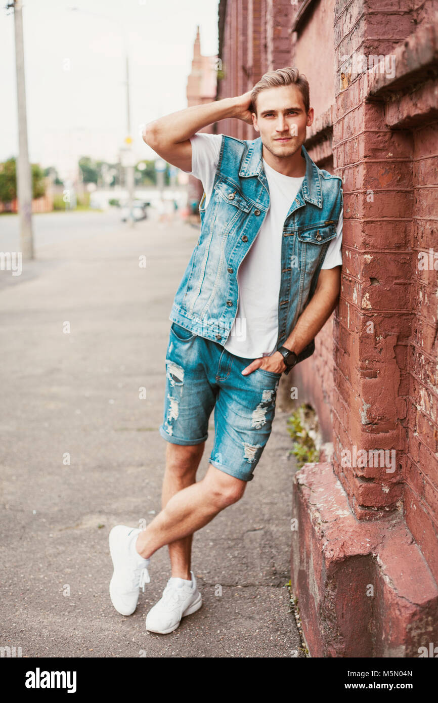 casual young man stands with his back against a brick wall Stock Photo ...