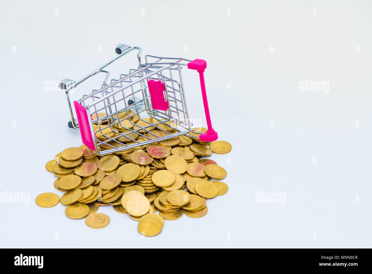 Stack of coins and shopping cart or supermarket trolley on white ...
