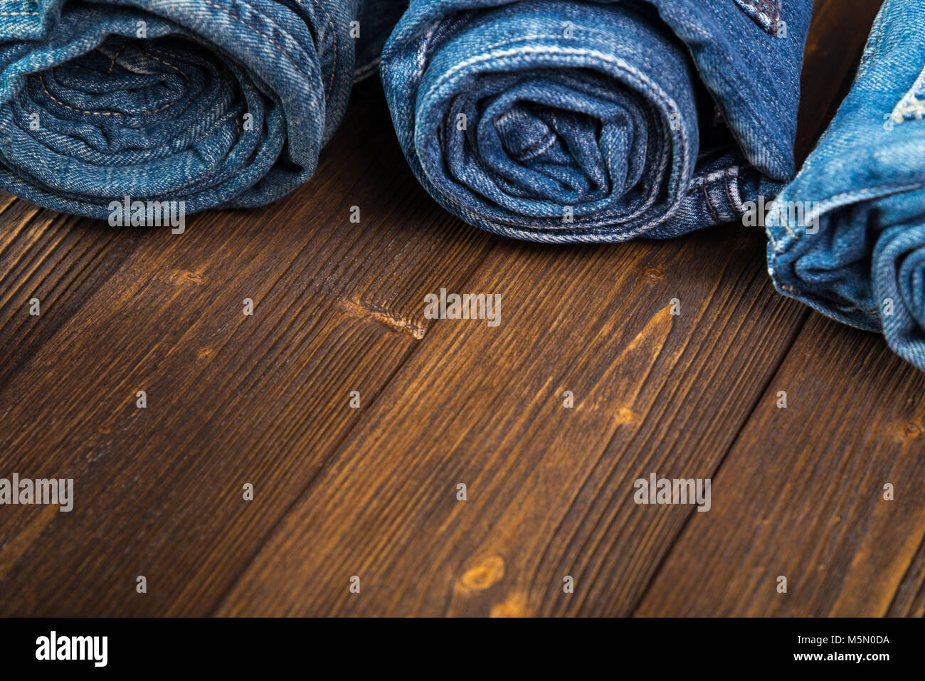 Roll Frayed jeans or blue jeans denim collection on rough dark wooden ...