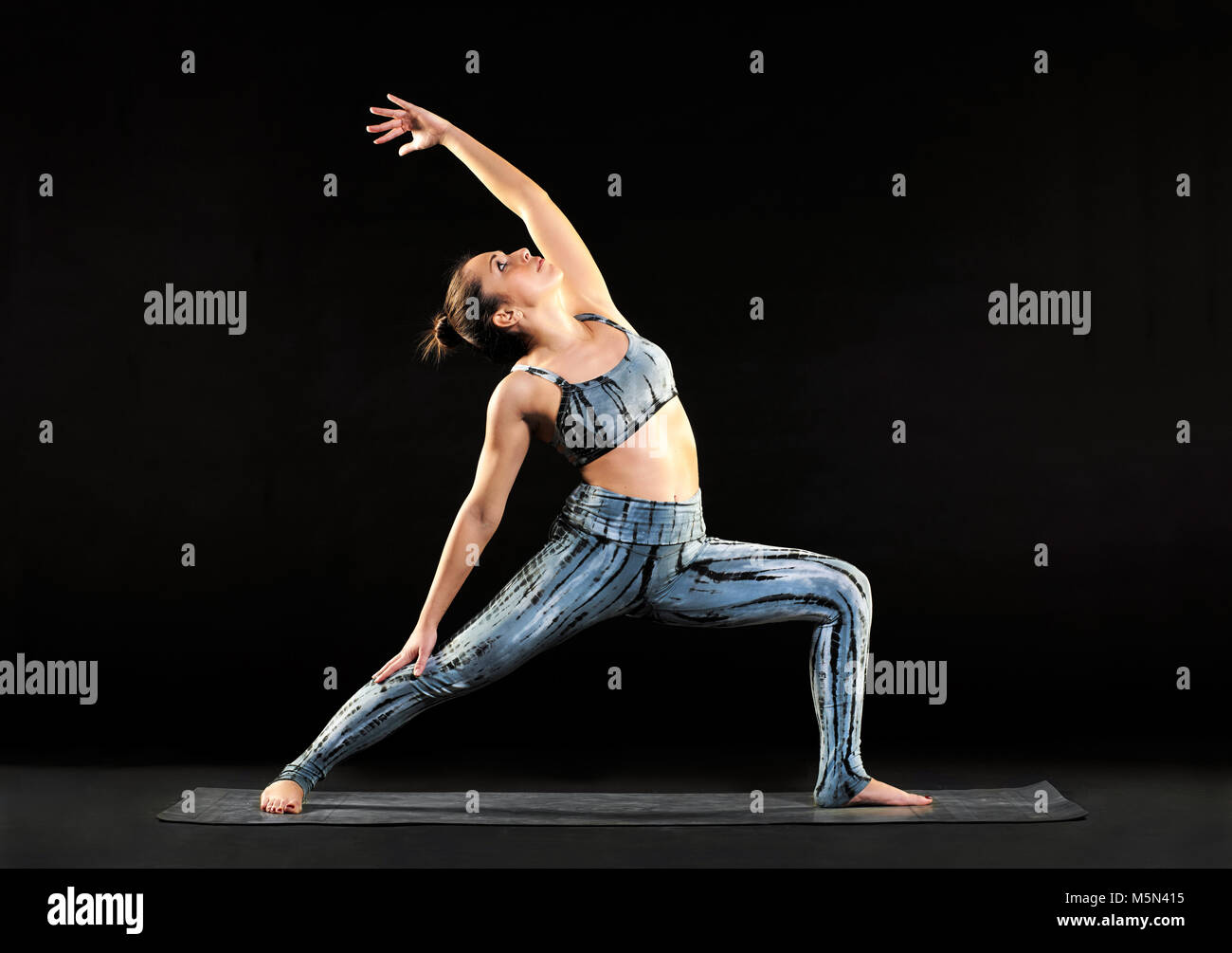 Young woman demonstrating a reverse warrior pose while doing yoga ...