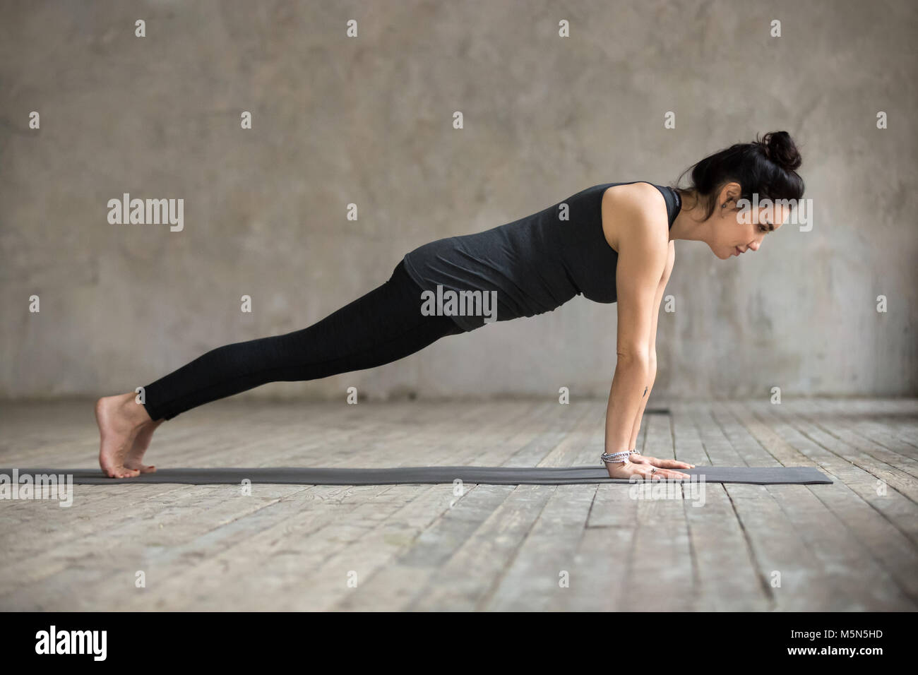 Young woman practicing yoga, doing Push ups or press ups exercise ...