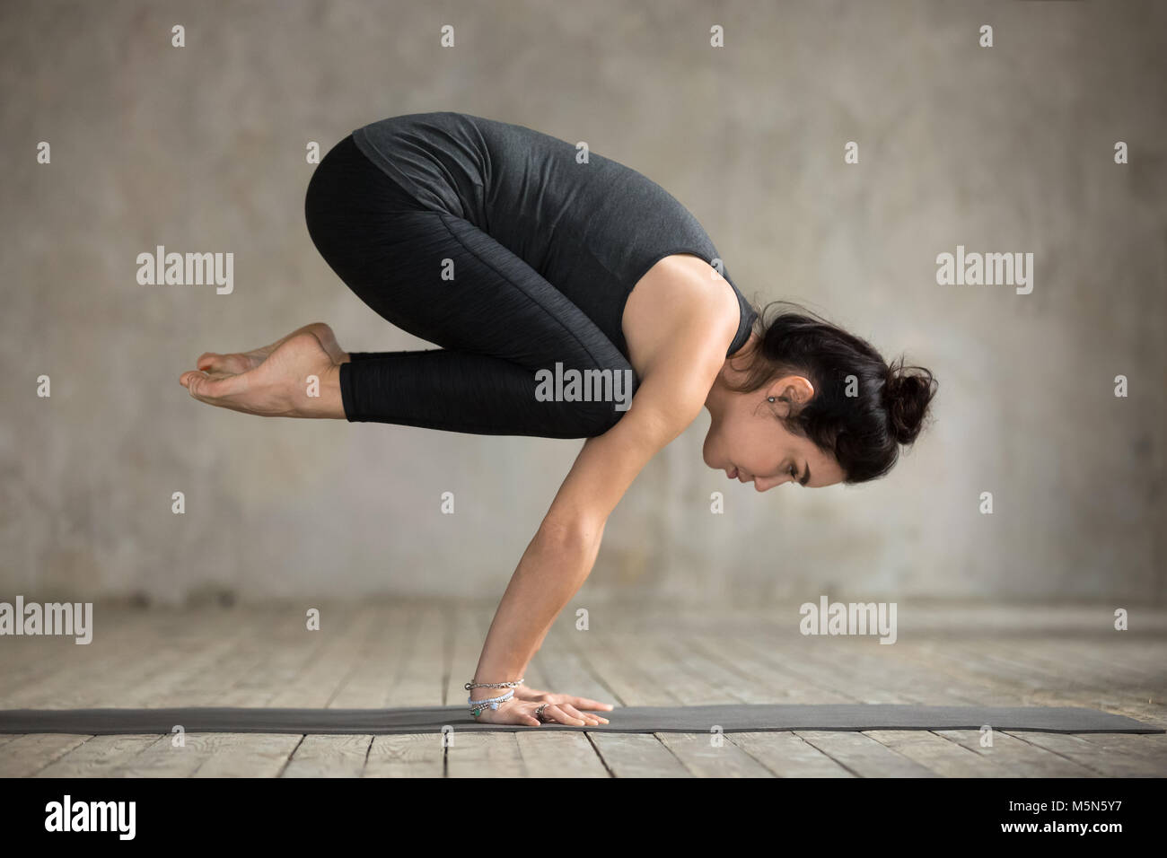 Young woman practicing yoga, doing Crane exercise, Bakasana pose ...