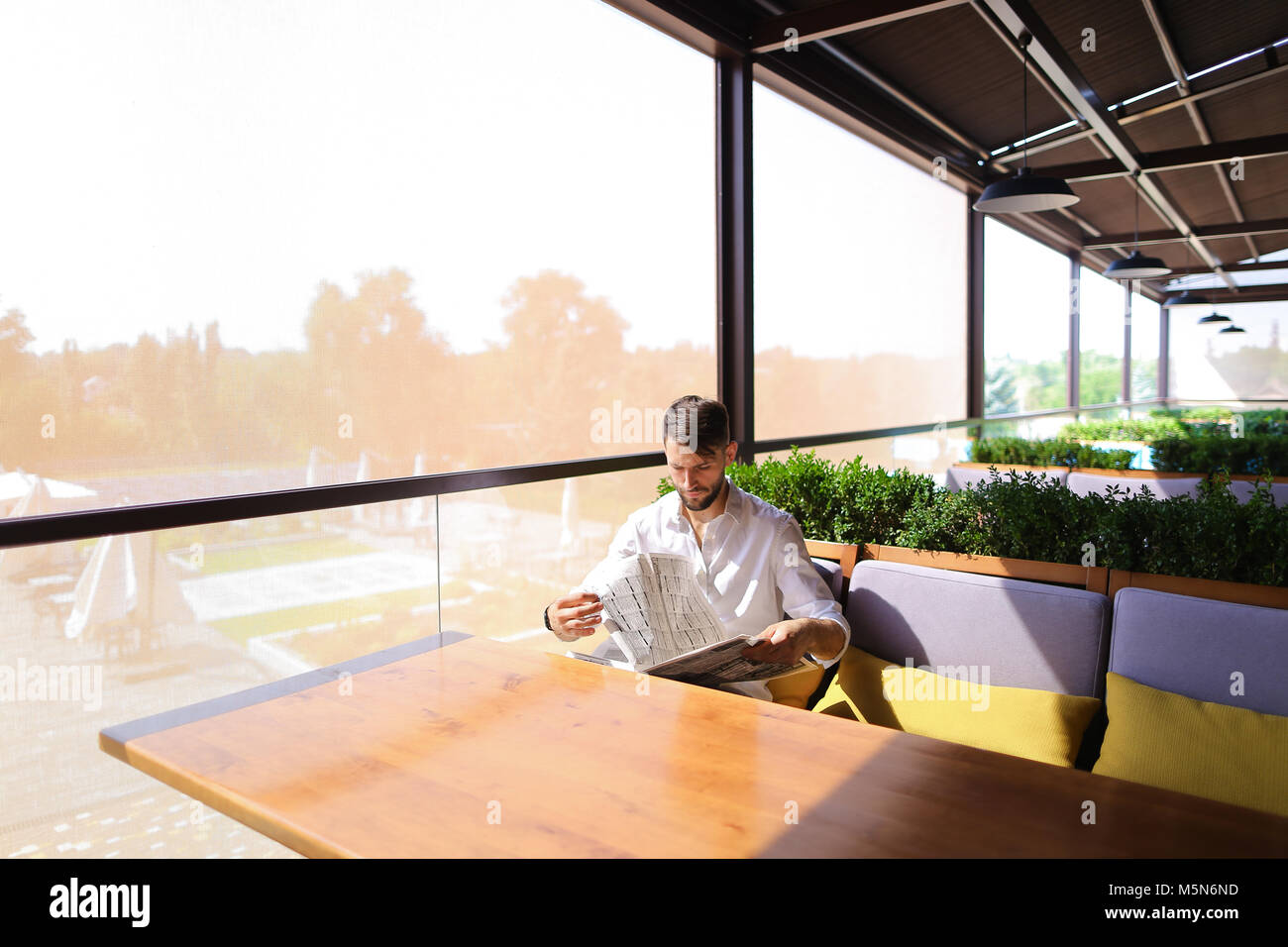 Prosperous man reading newspaper articles and resting Stock Photo - Alamy