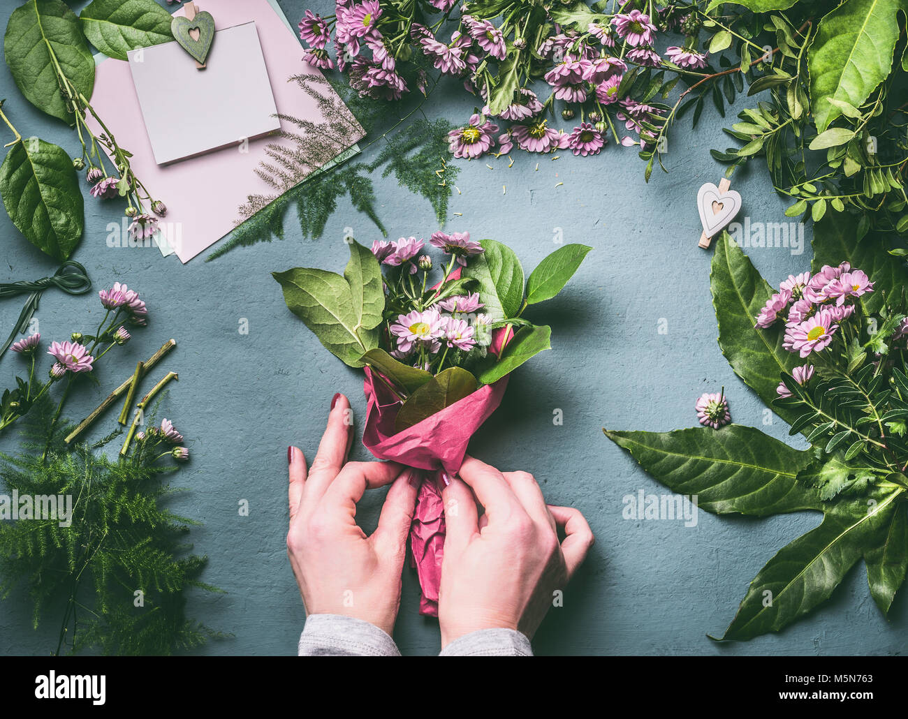 Female hands making flowers bouquet arrangement on working gray table ...
