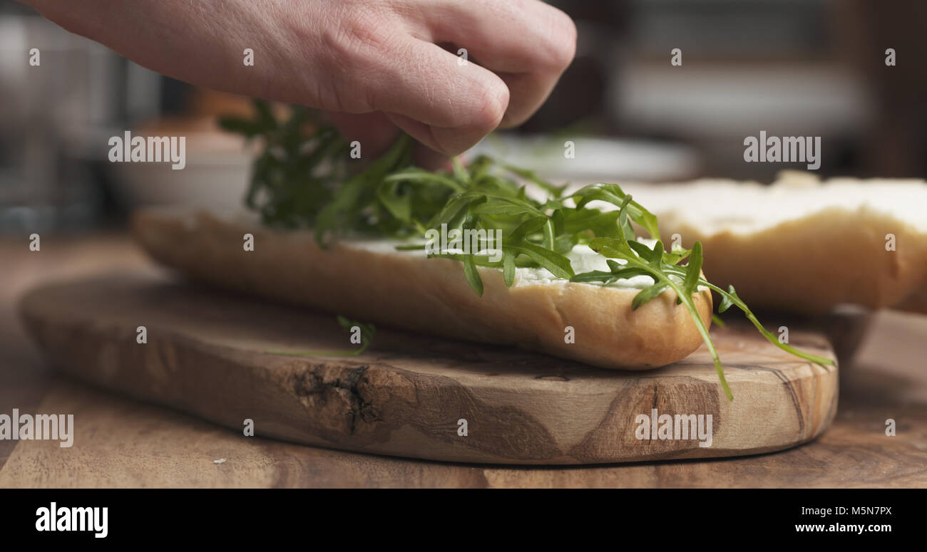 man hands put arugula on baguette on wood board, wide photo Stock Photo ...