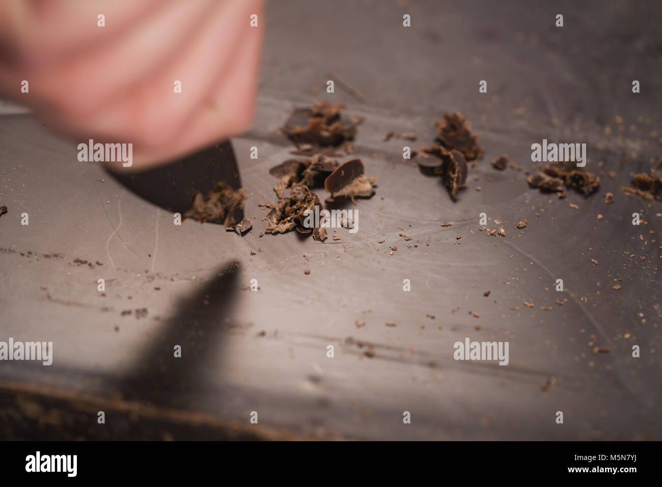 cutting industrial block of dark chocolate with knife, closeup photo ...