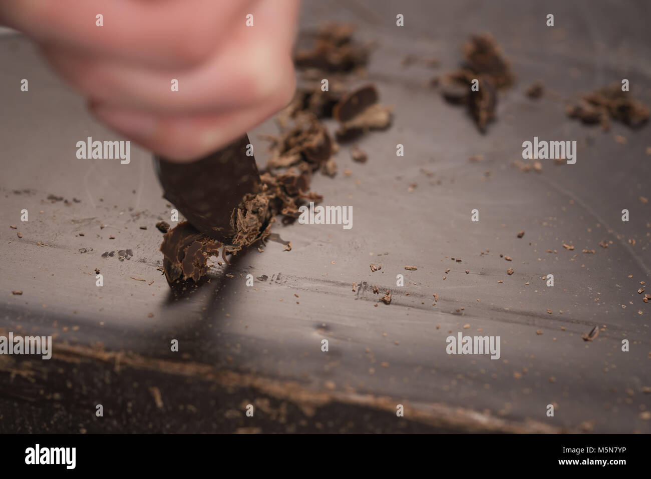 cutting industrial block of dark chocolate with knife, closeup photo ...