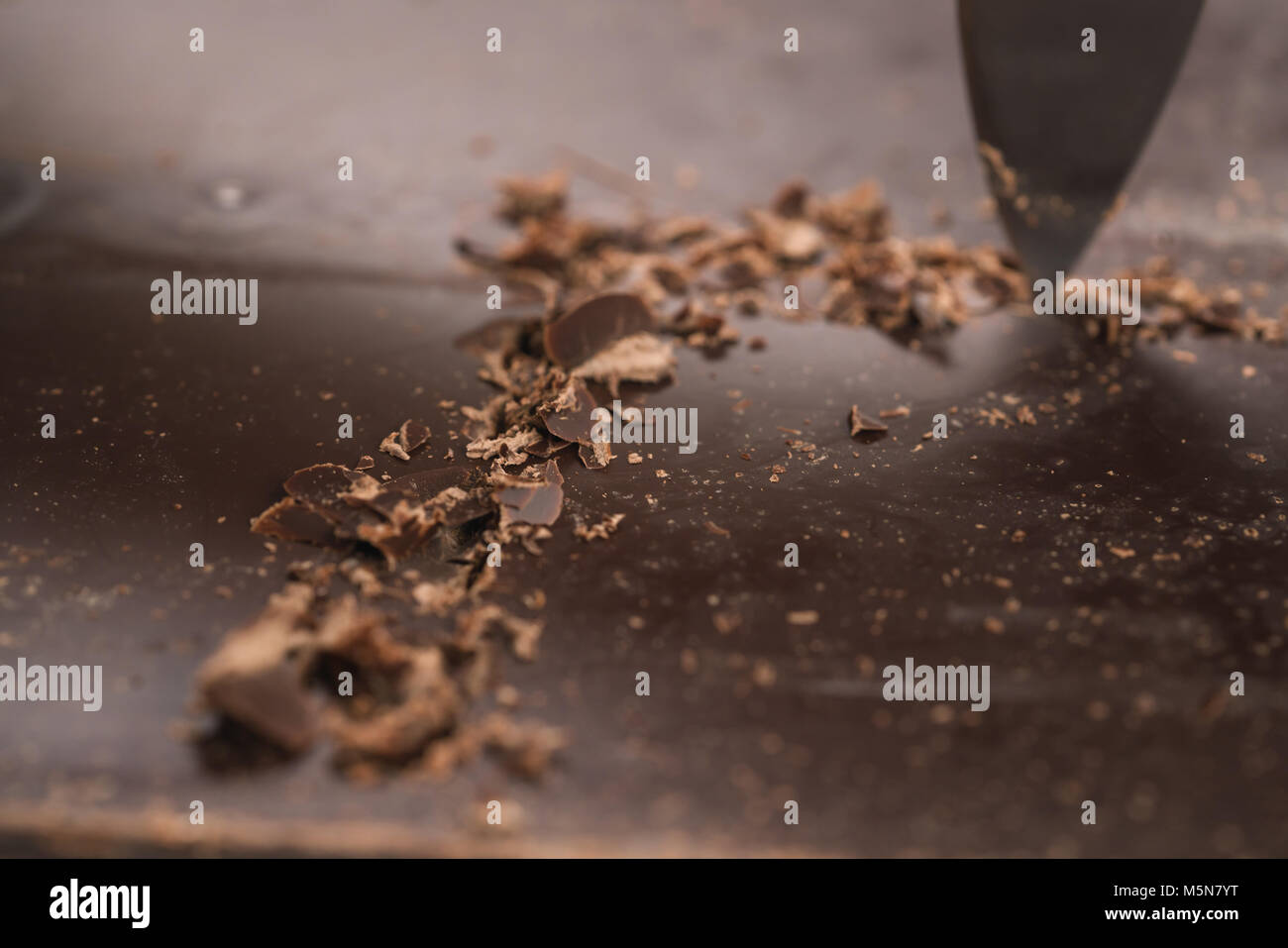 cutting industrial block of dark chocolate with knife, closeup photo ...