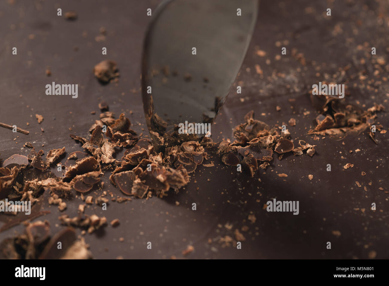 cutting industrial block of dark chocolate with knife, closeup photo ...
