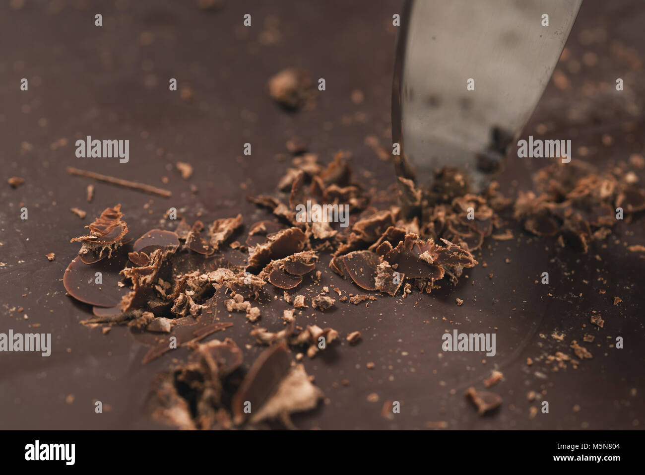 cutting industrial block of dark chocolate with knife, closeup photo ...