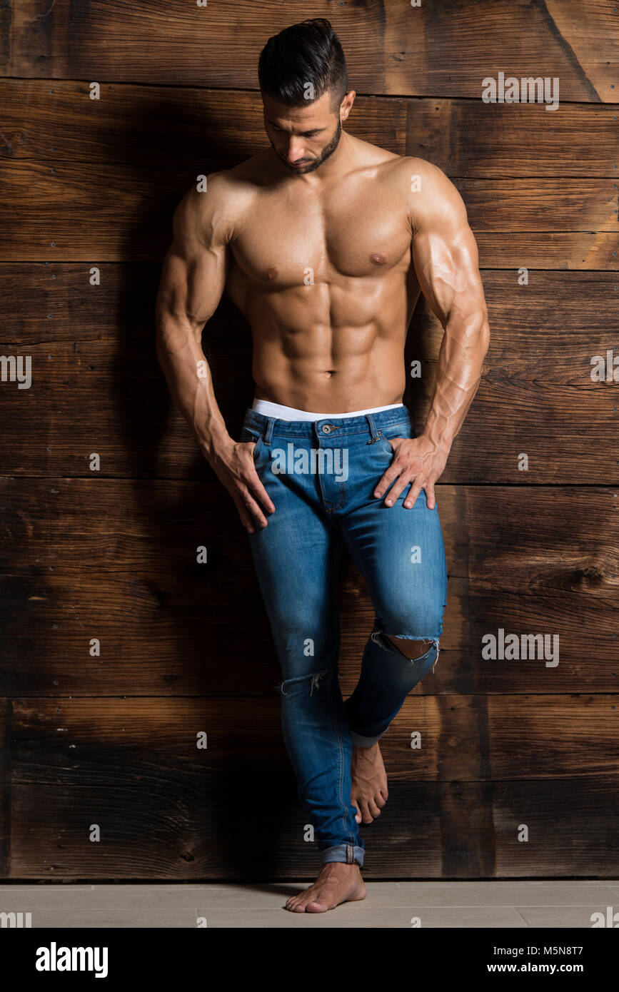 Healthy Young Man Standing Strong Against a Wooden Wall and Flexing ...
