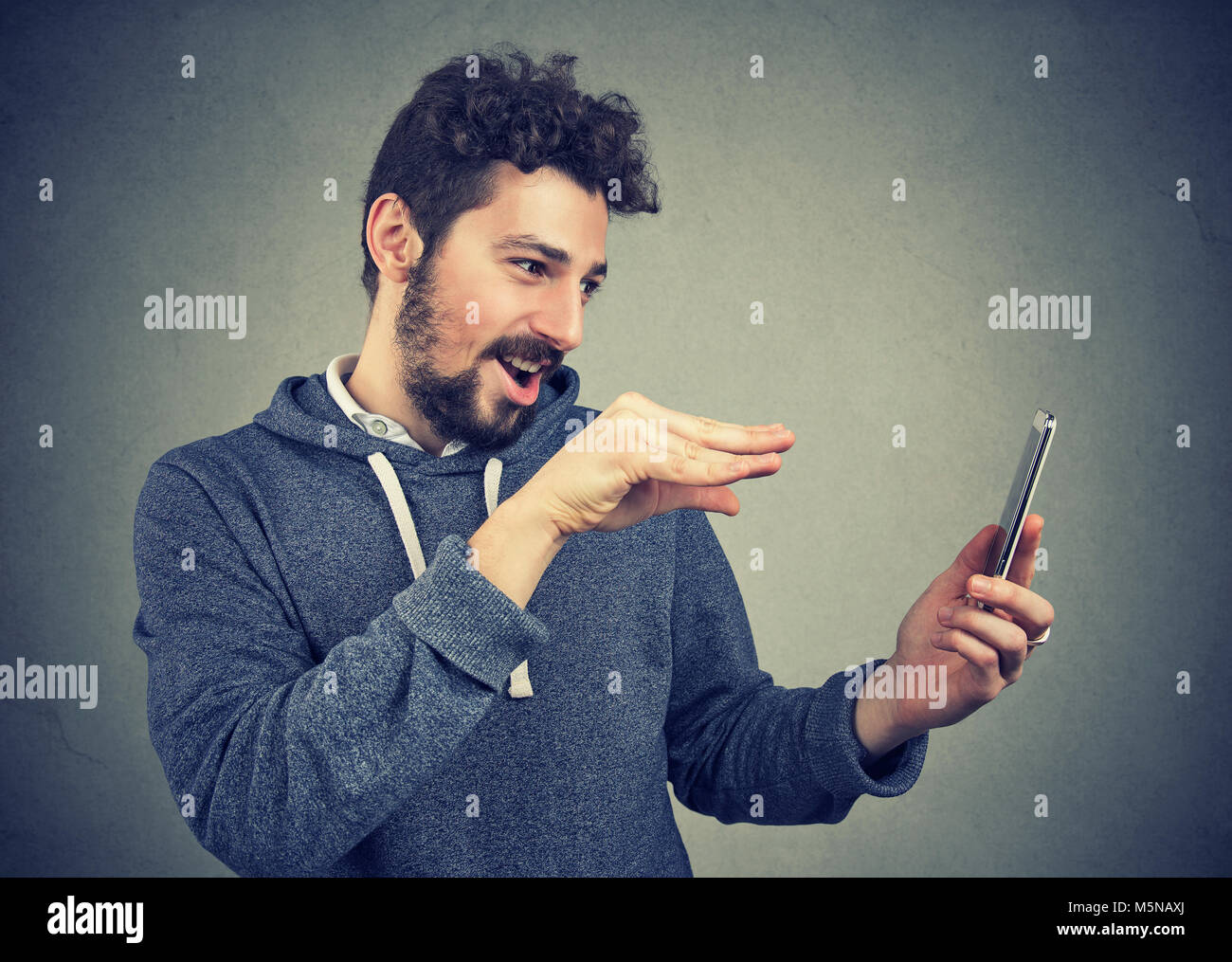 Young expressive man manipulating with gadget using magic and standing ...