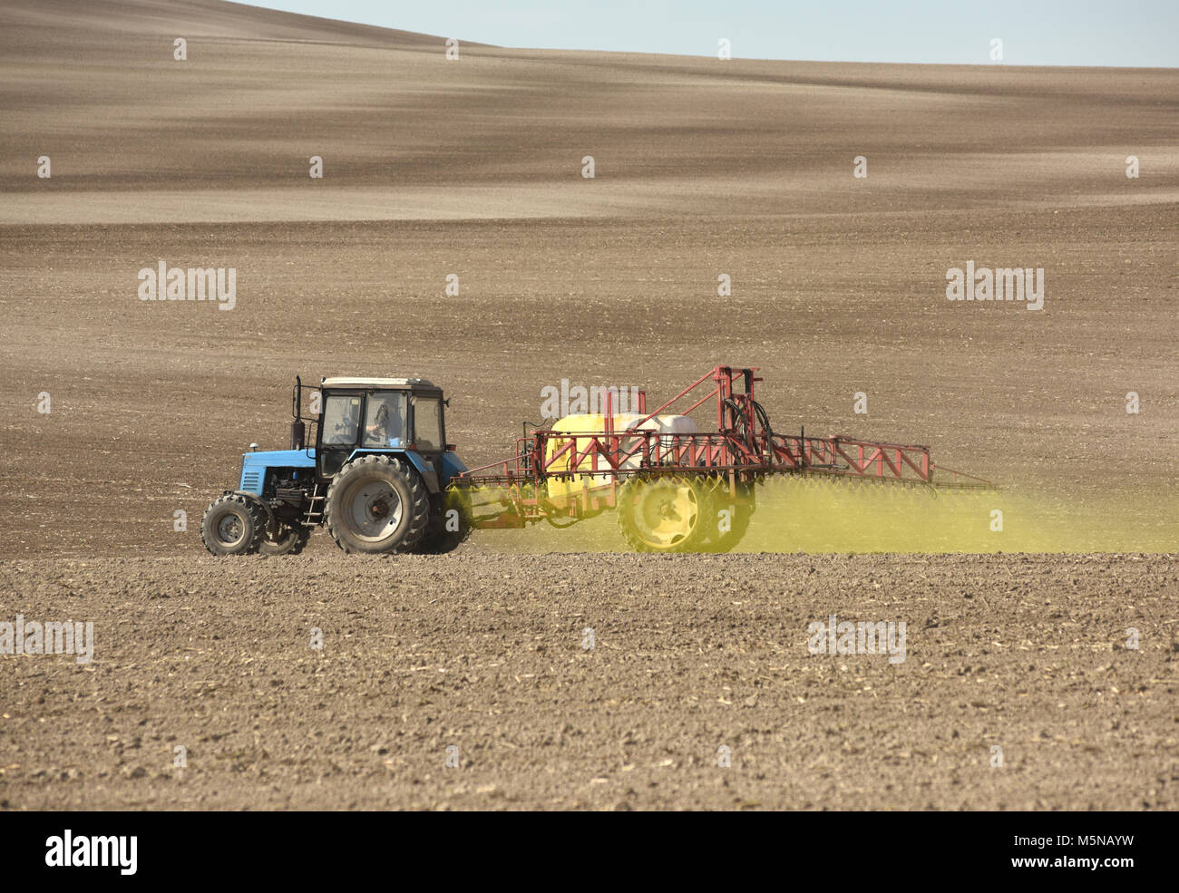 tractor spraying the chemicals on the field. tractor sprinkling ...