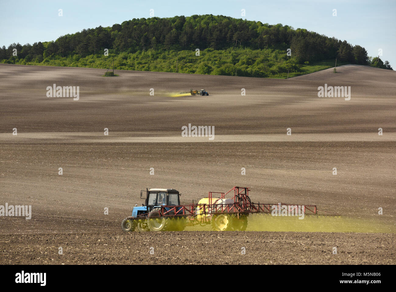 tractor spraying the chemicals on the field. tractor sprinkling ...