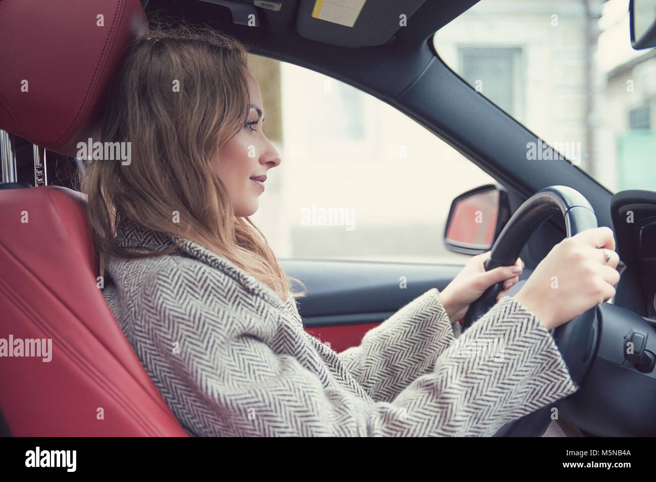 Side view of elegant successful woman sitting inside of car and driving ...
