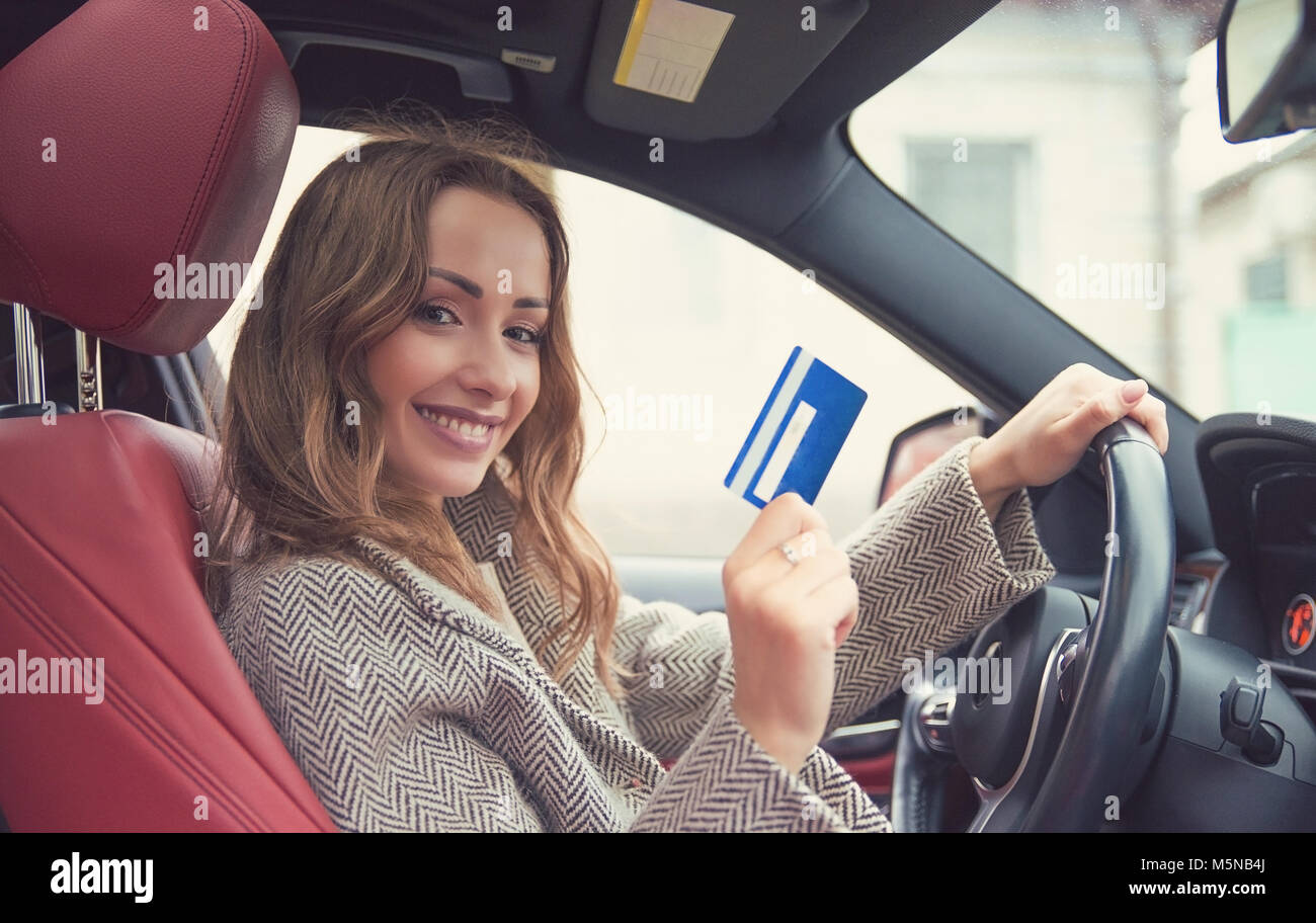 Happy young woman sitting inside her new car showing credit card Stock ...