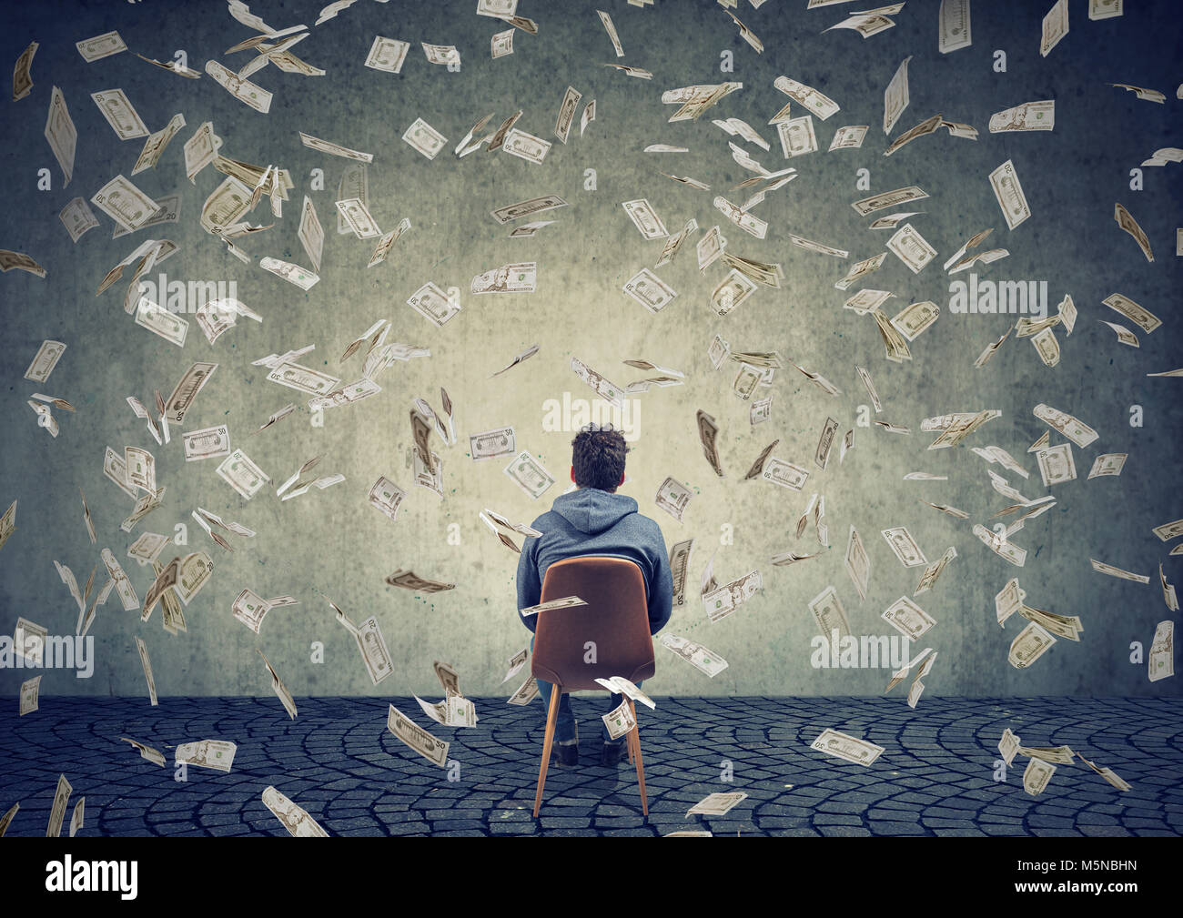 Rear back view of casual man sitting in front of a wall under money ...