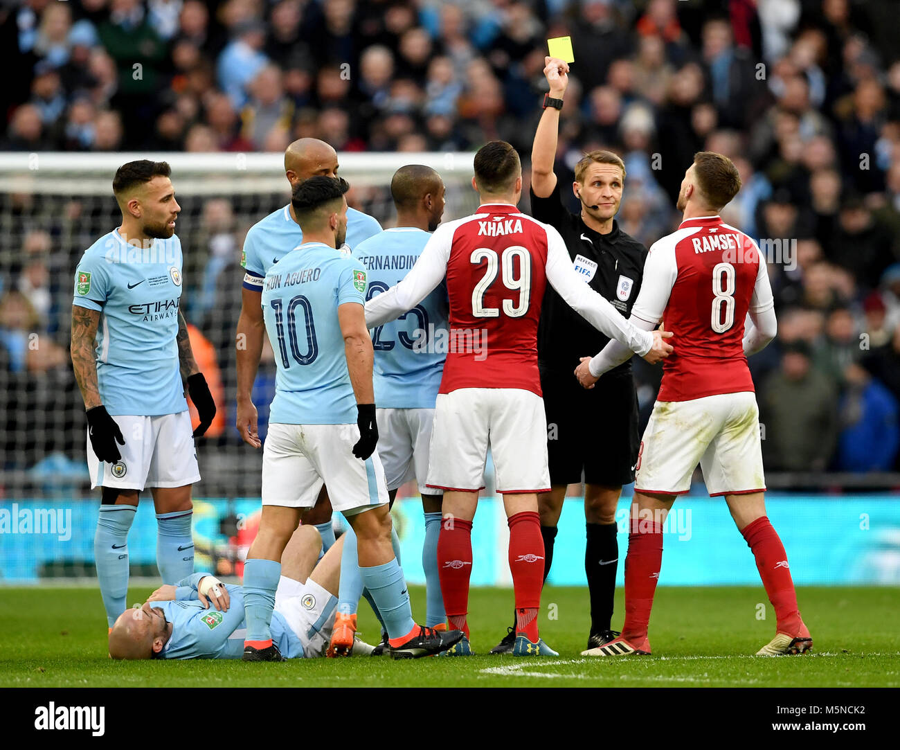 Match referee Craig Pawson (second right) gives a yellow card to Arsenal's Aaron Ramsey (right ...