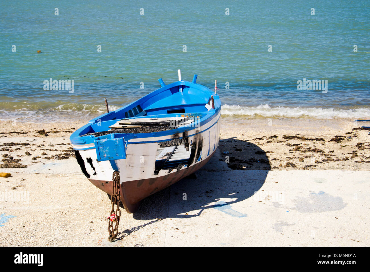 Little blue burnt boat on the beach Stock Photo - Alamy