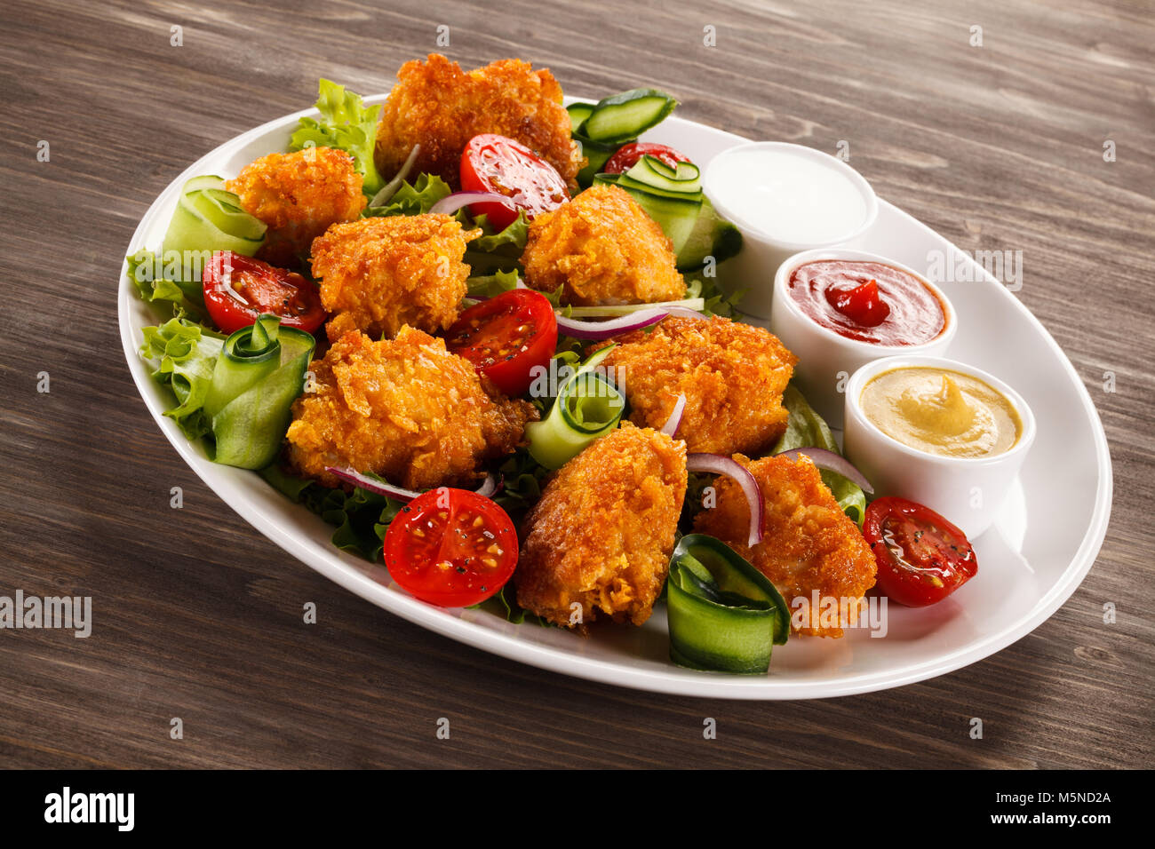 Fried chicken nuggets and vegetables on wooden table Stock Photo - Alamy