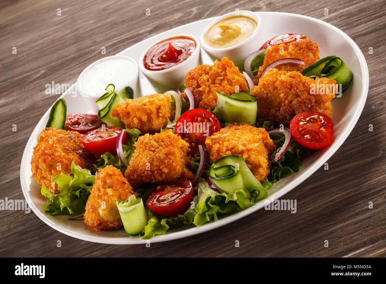 Fried chicken nuggets and vegetables on wooden table Stock Photo - Alamy