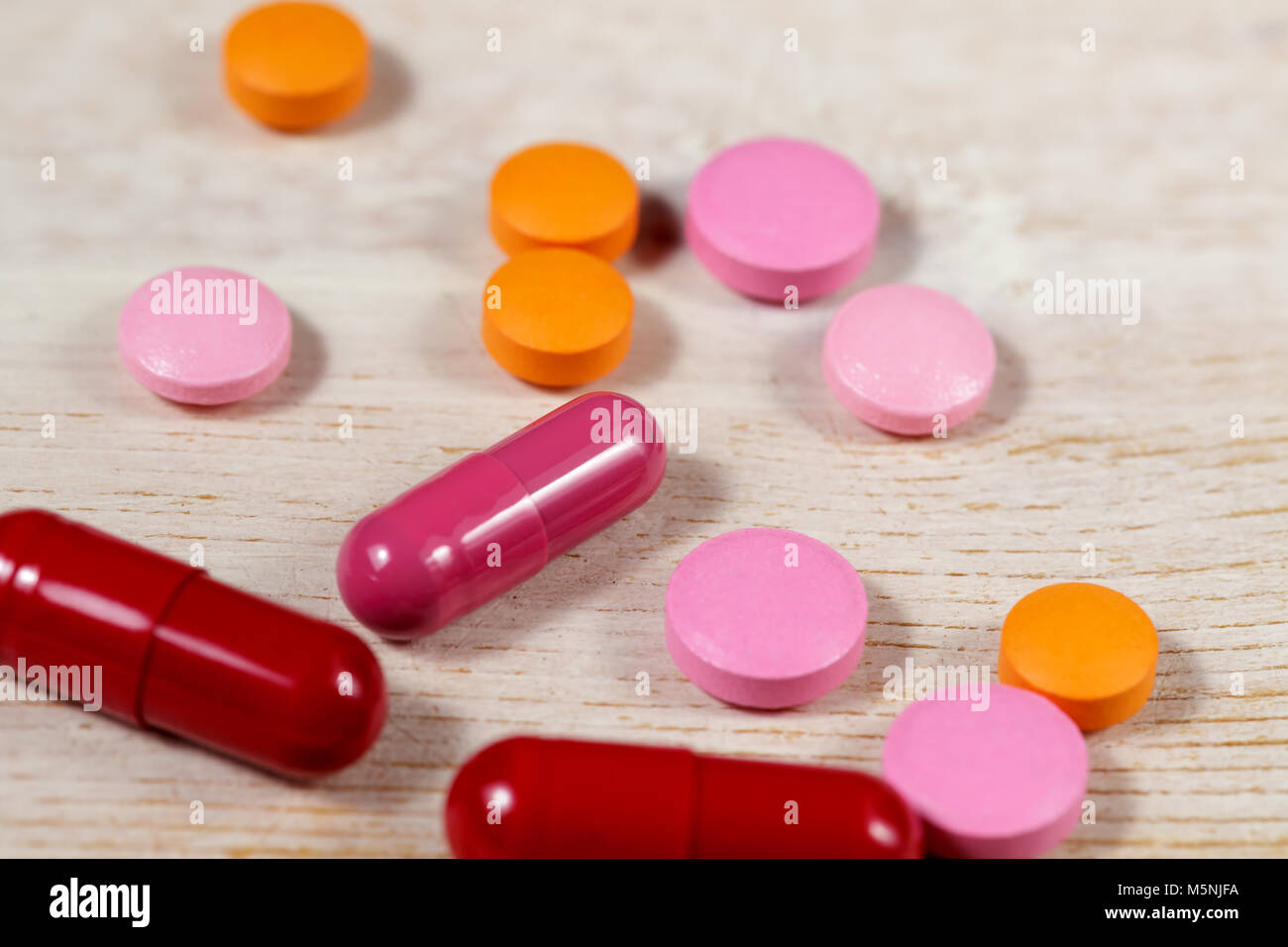 Red capsules and round color pills Stock Photo - Alamy