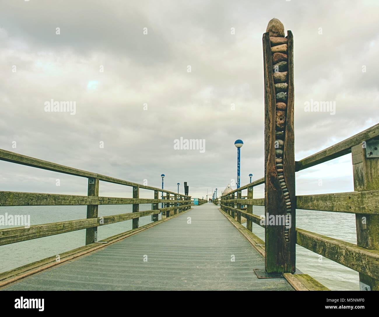 Empty wooden pier in harbor. Steel lamp post, horizon hidden in thick ...