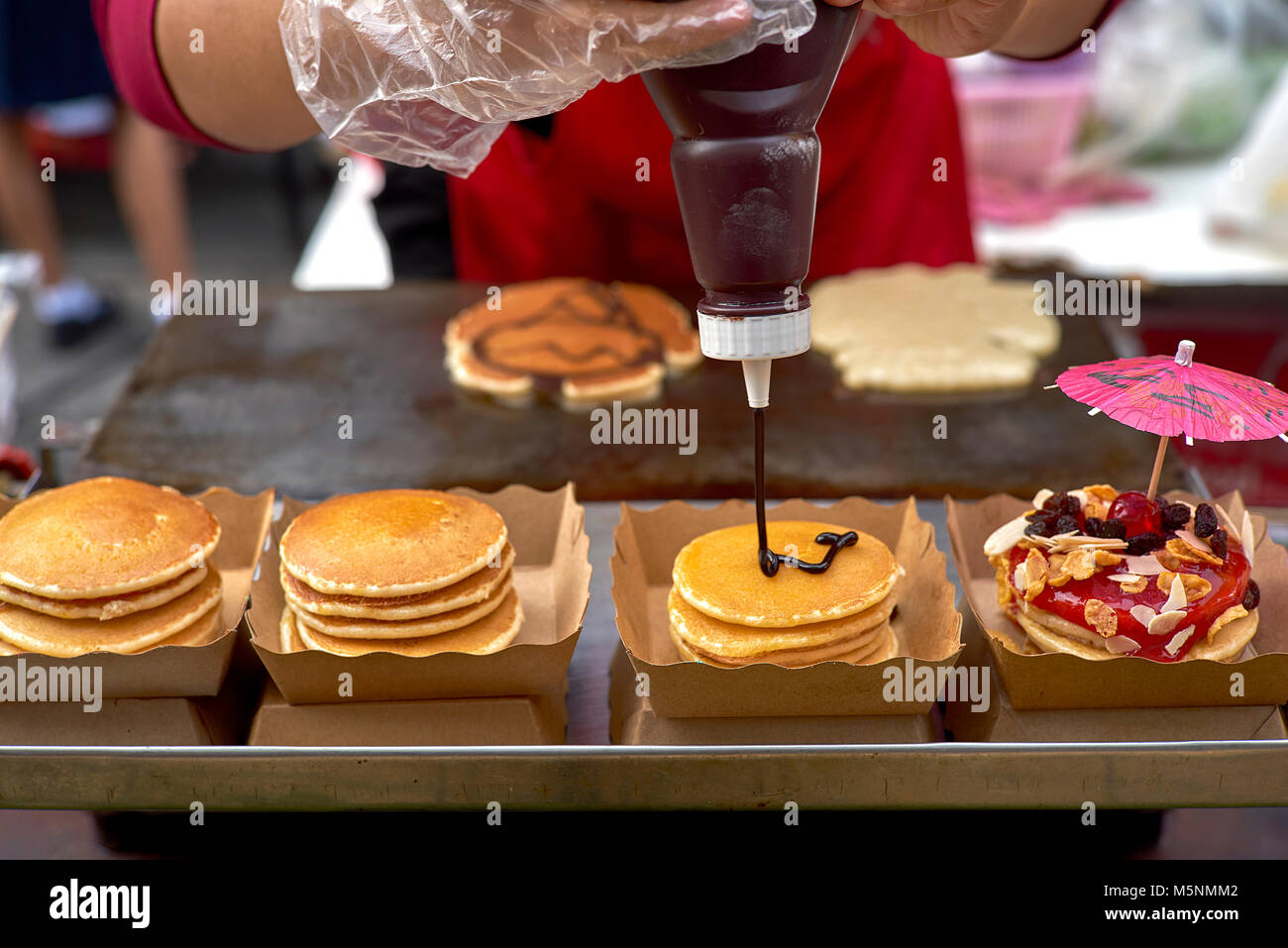 Thailand street food vendor preparing and decorating filled pancakes ...