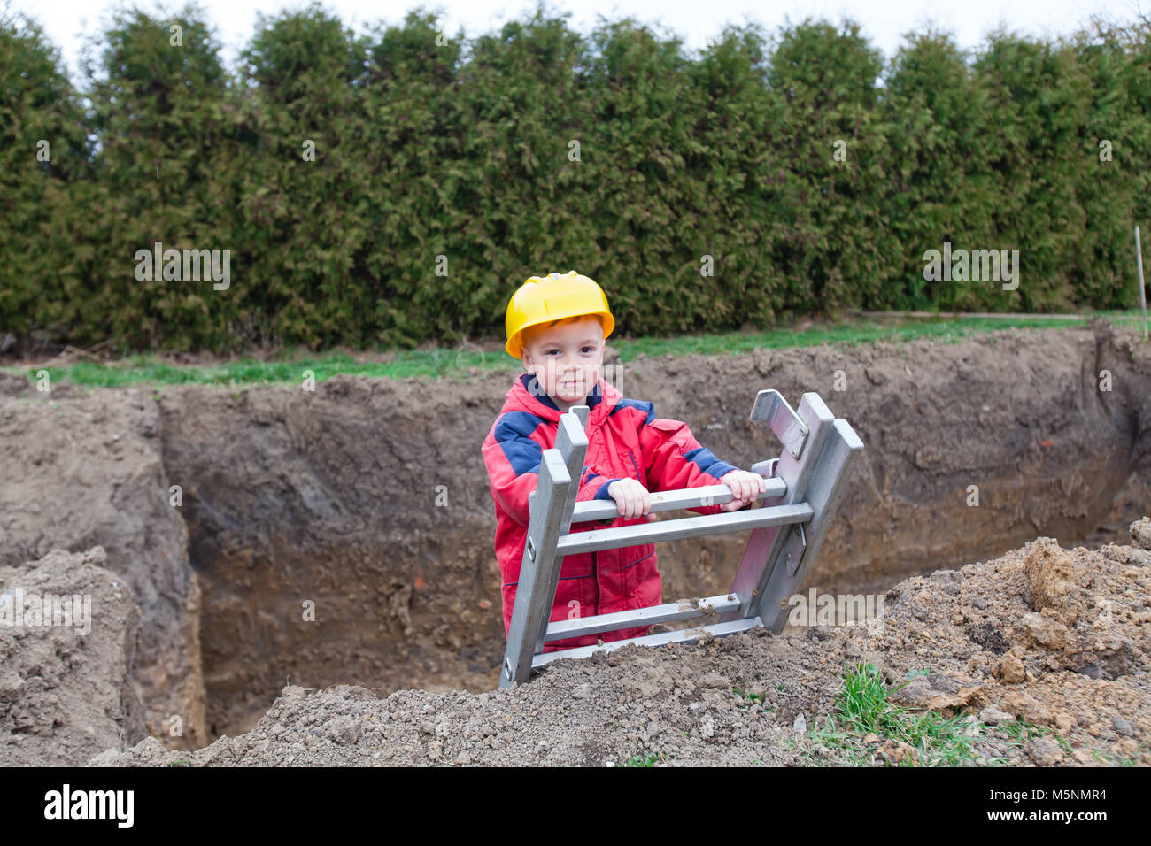 Little boy with a spade helps parents during the construction of the ...