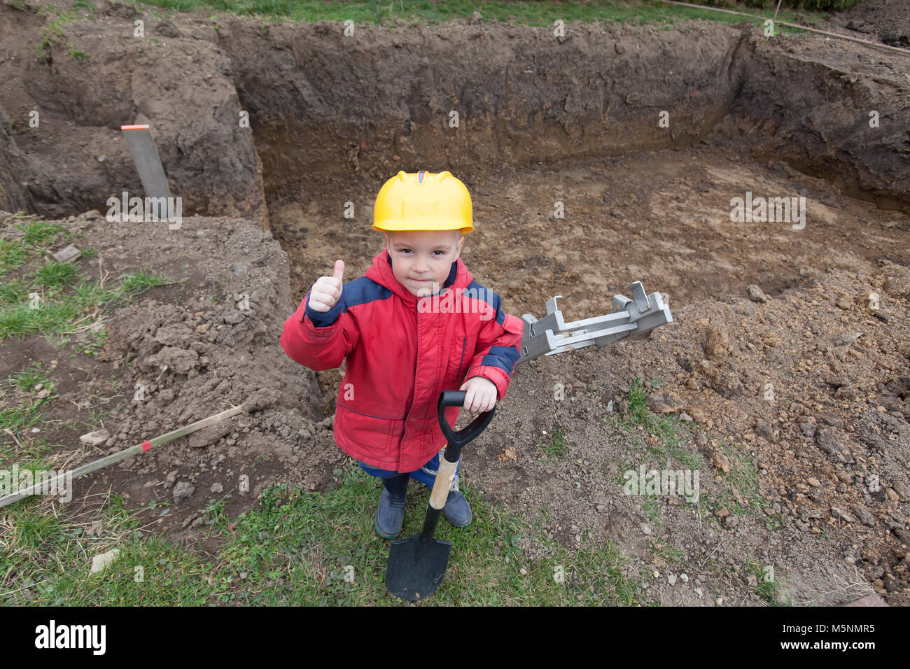 Little boy with a spade helps parents during the construction of the ...