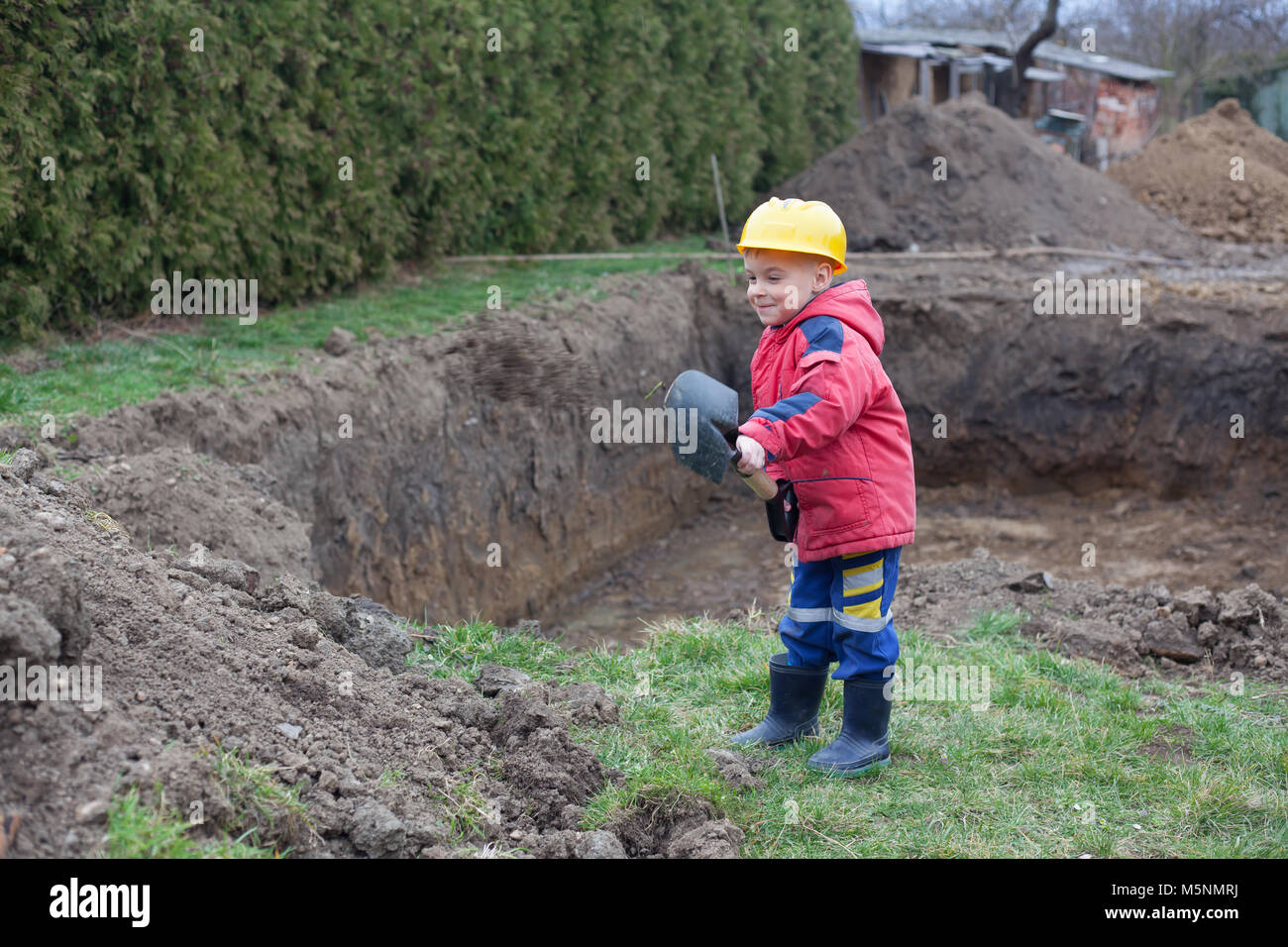 Little boy with a spade helps parents during the construction of the ...