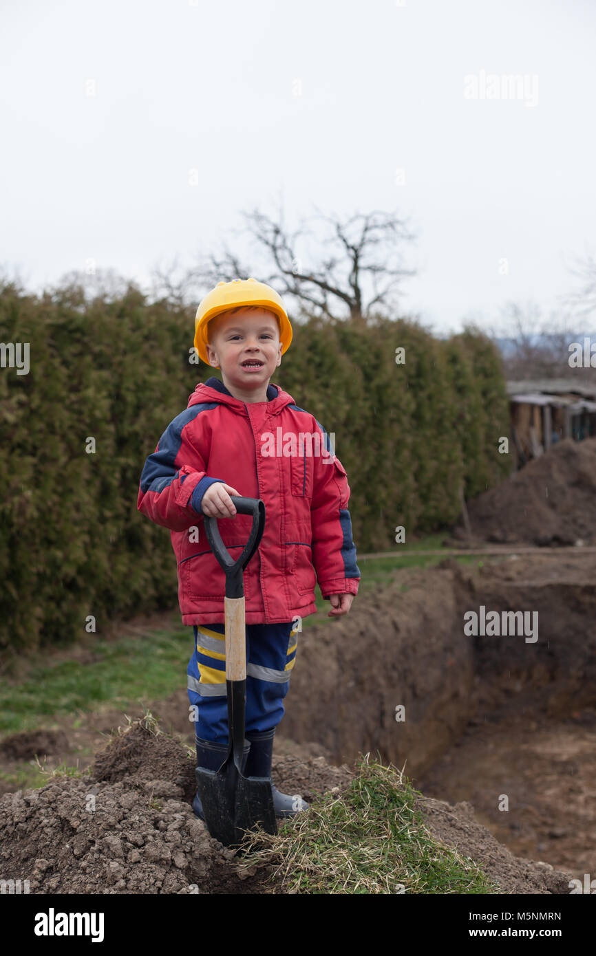 Little boy with a spade helps parents during the construction of the ...