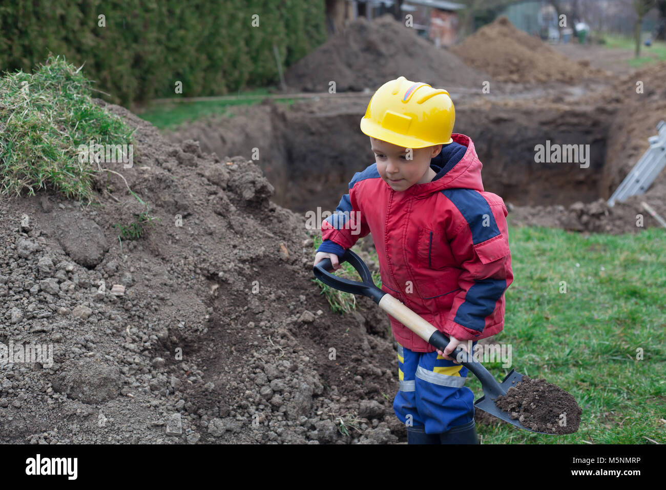 Little boy with a spade helps parents during the construction of the ...
