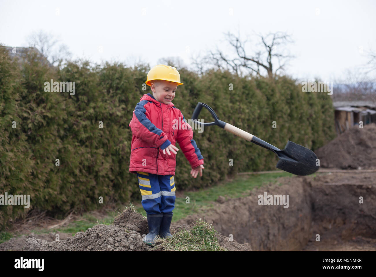 Little boy with a spade helps parents during the construction of the ...