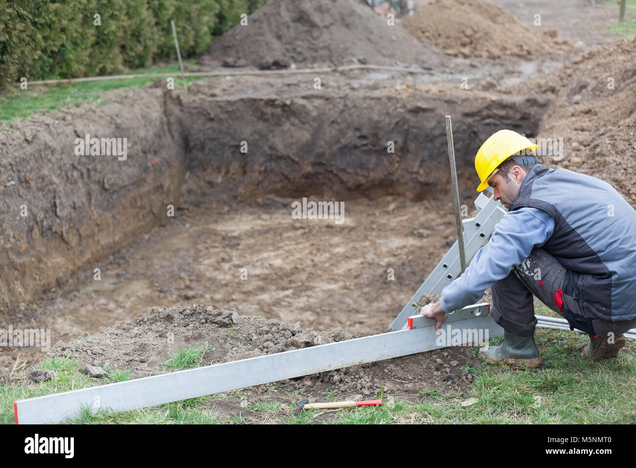 Man working on building a house with a private pool Stock Photo - Alamy