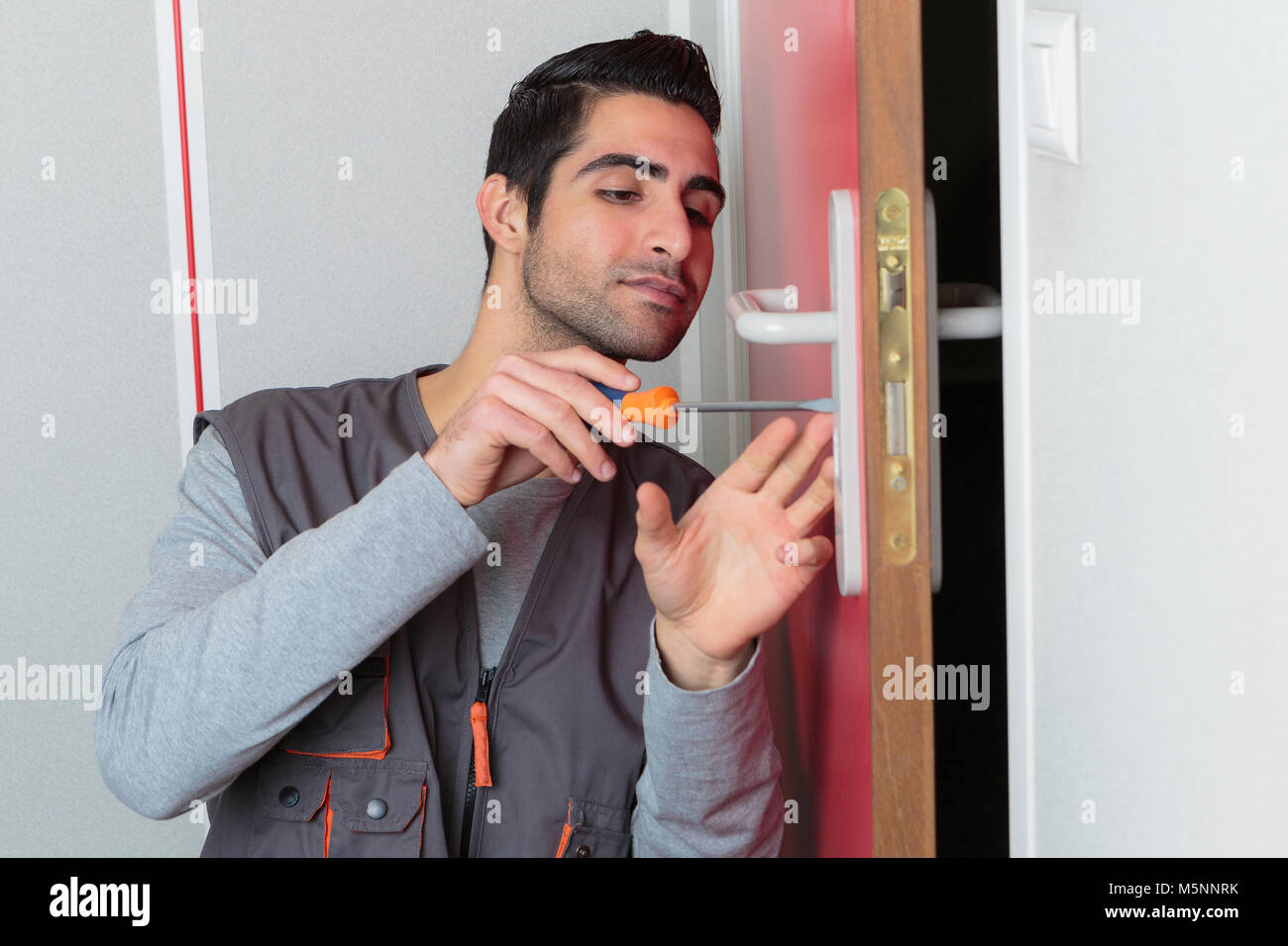 happy young carpenter fixing broken door lock Stock Photo - Alamy
