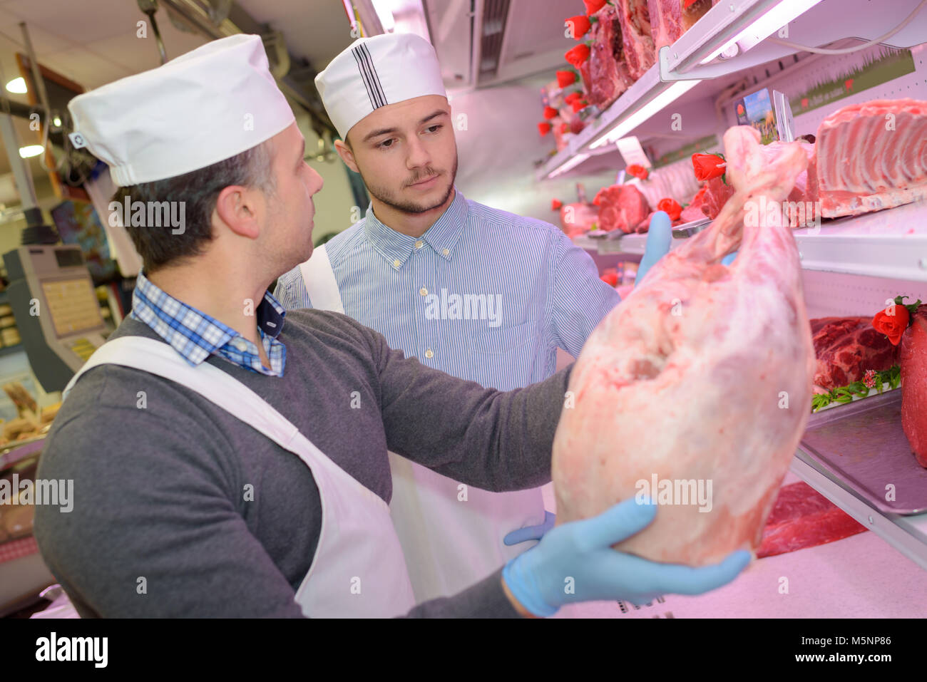 butcher teaching a young one how to sell meat Stock Photo - Alamy