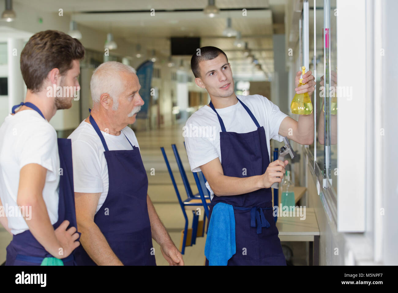male cleaning team cleaning notice board Stock Photo - Alamy