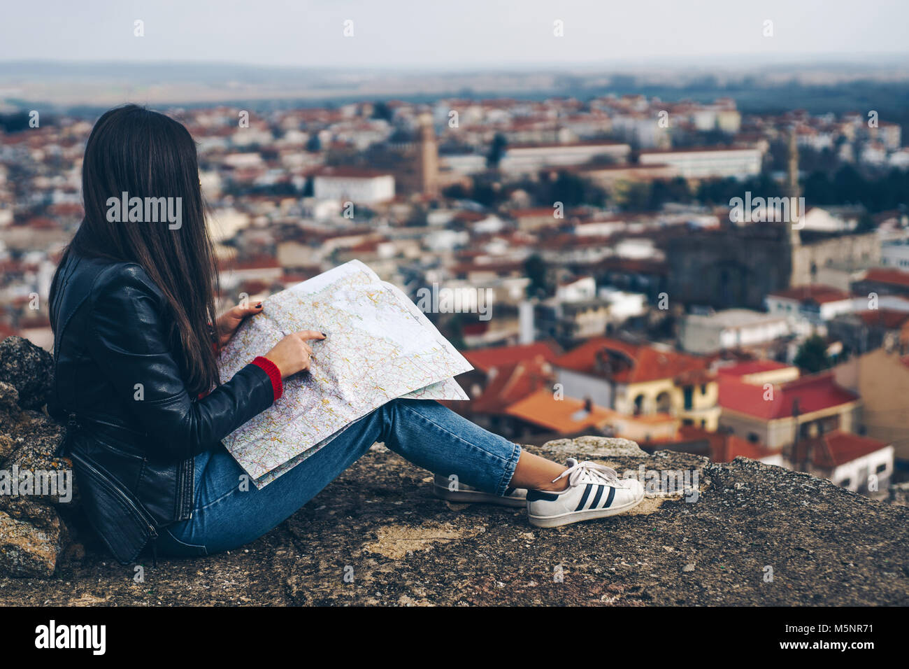 Young girl standing in front of beautiful city view and looking at the ...