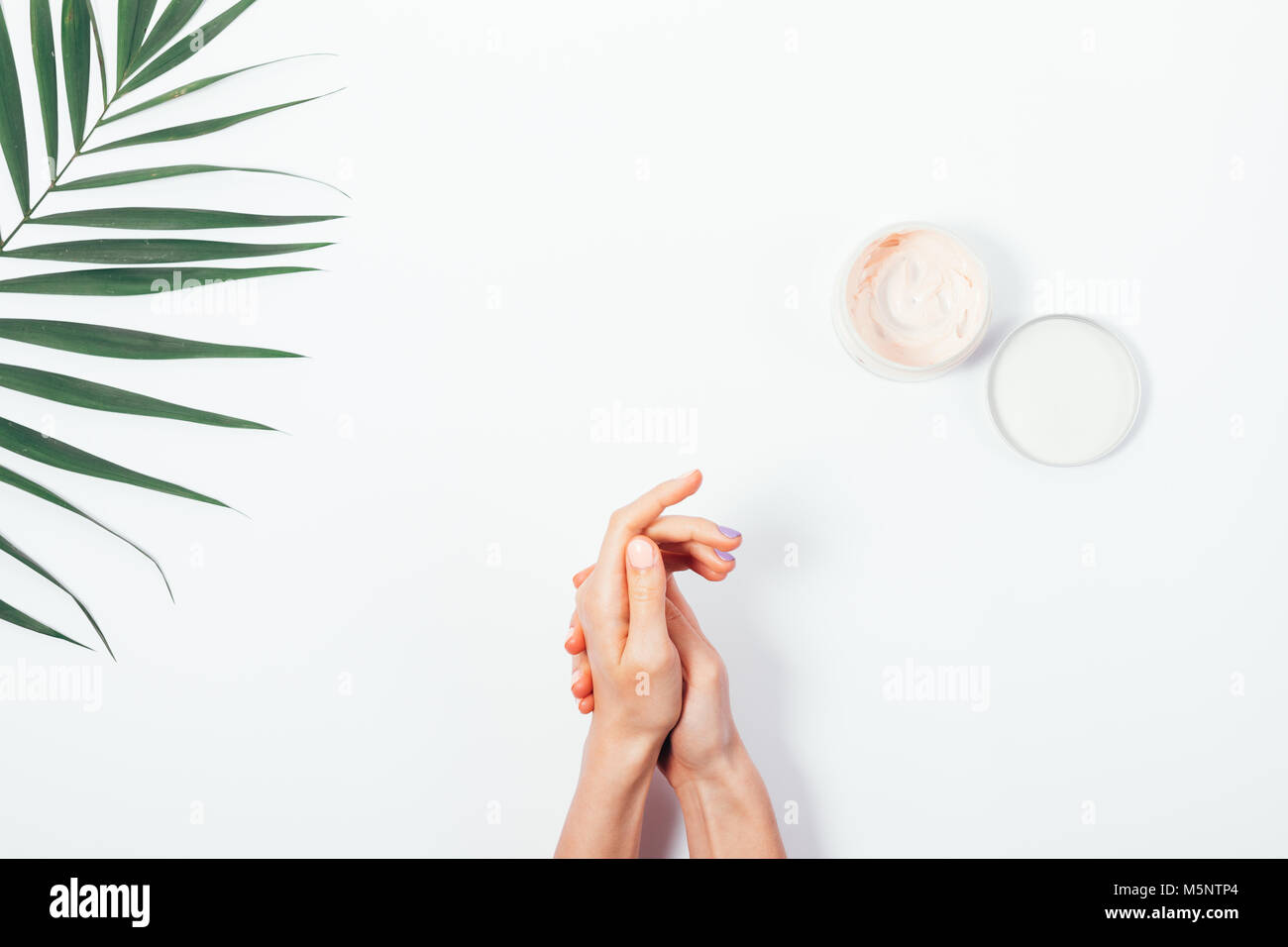 Woman rubbing cream into the skin of hands on a white background top ...