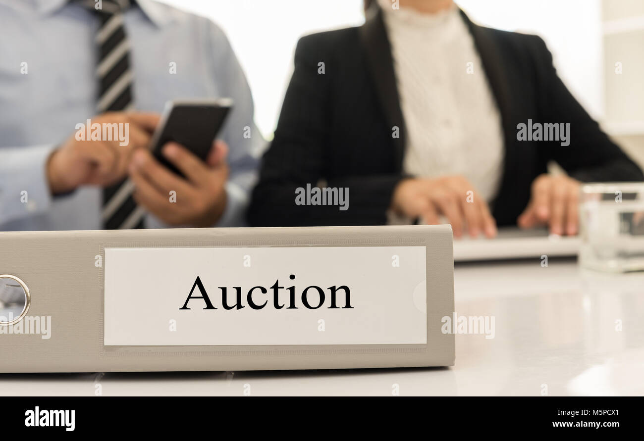 closeup auction file with two business person bidding via electronic ...