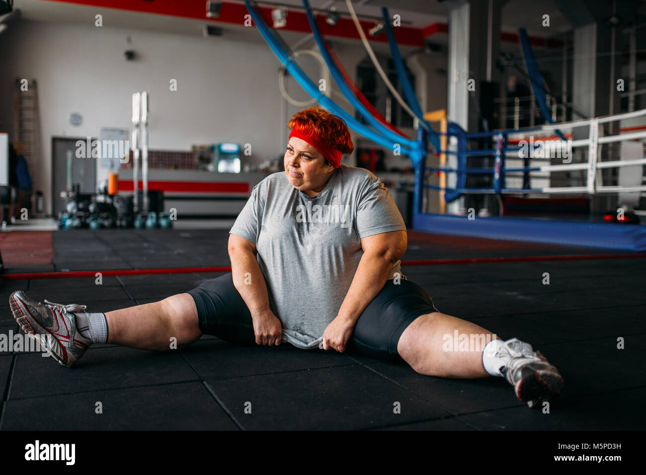 Overweight woman, exercises on the floor, workout in gym. Calories ...