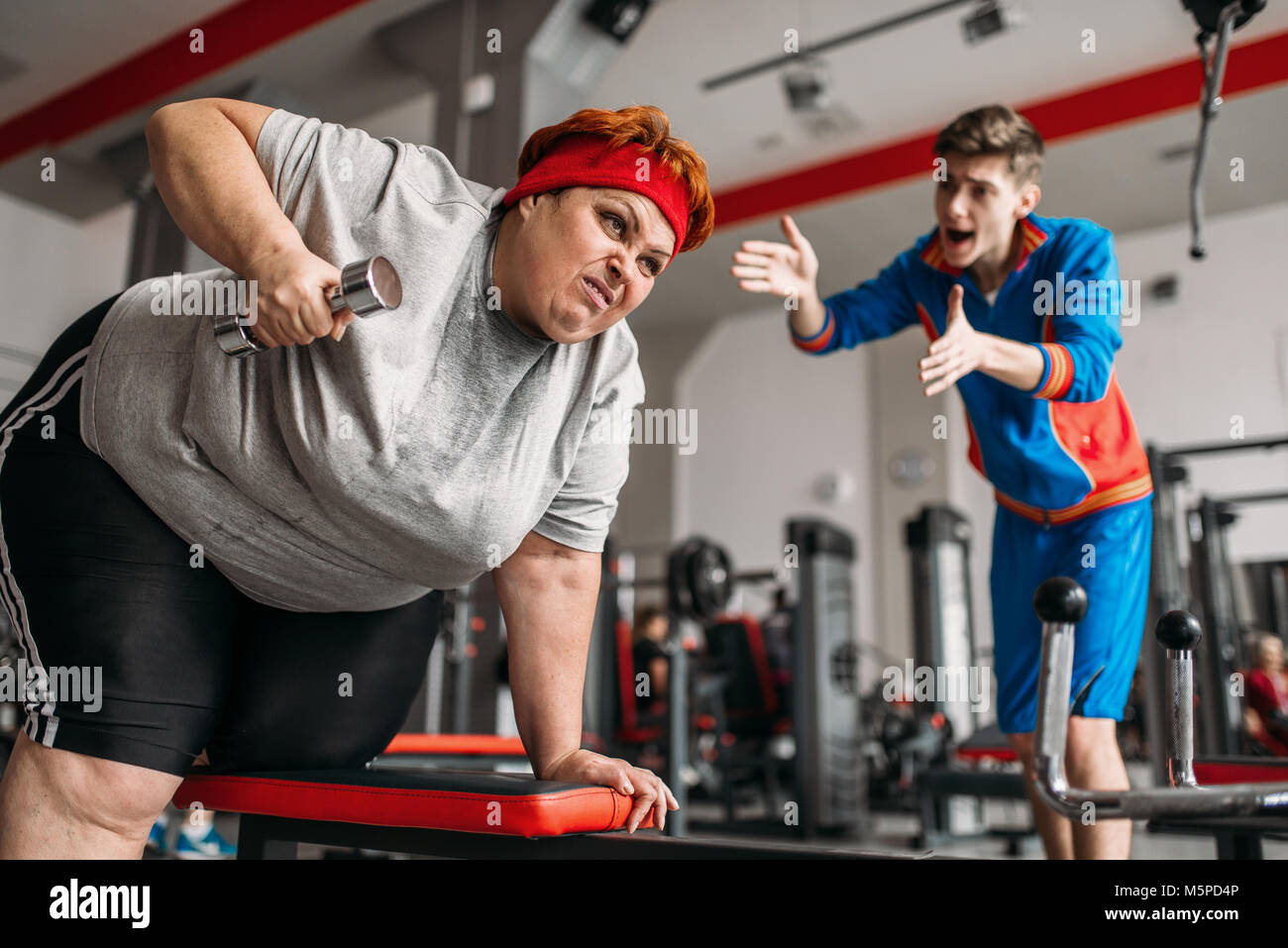 Instructor forces fat woman to exercise with dumbbells in gym. Calories ...